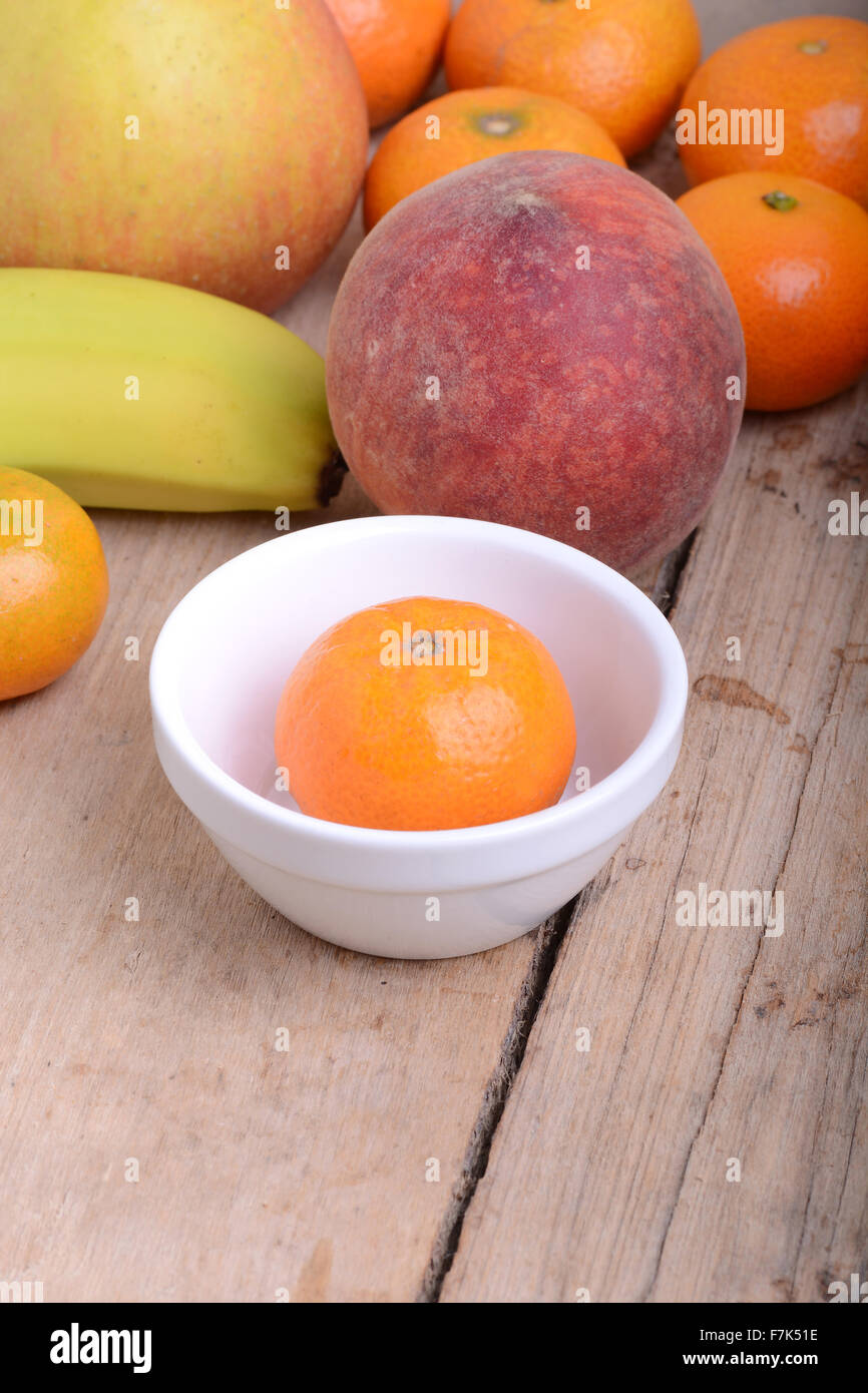 Mandarin Apples Bananas Peach on wooden plate Stock Photo - Alamy