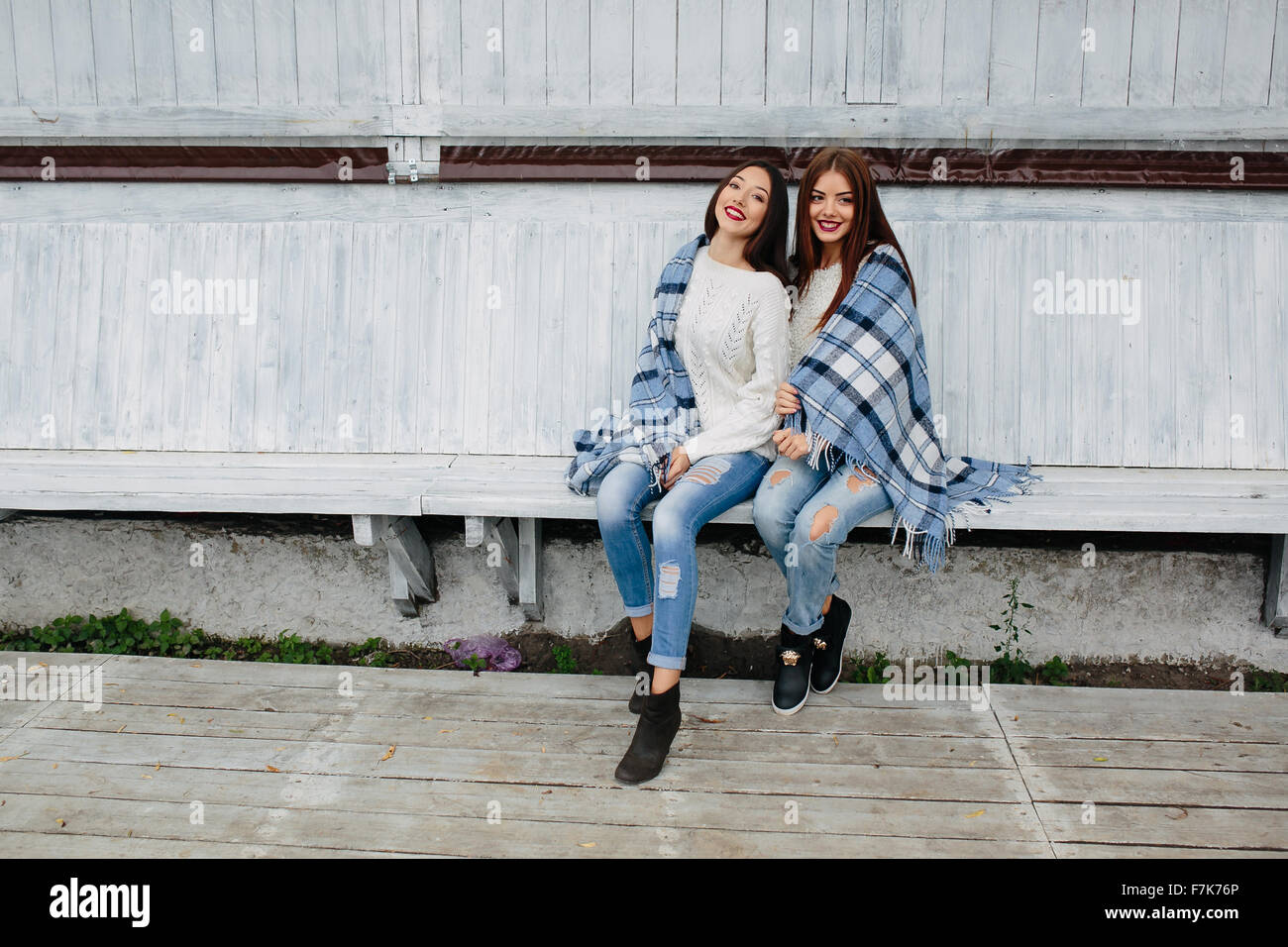 Two girls sit on a bench in the park Stock Photo - Alamy
