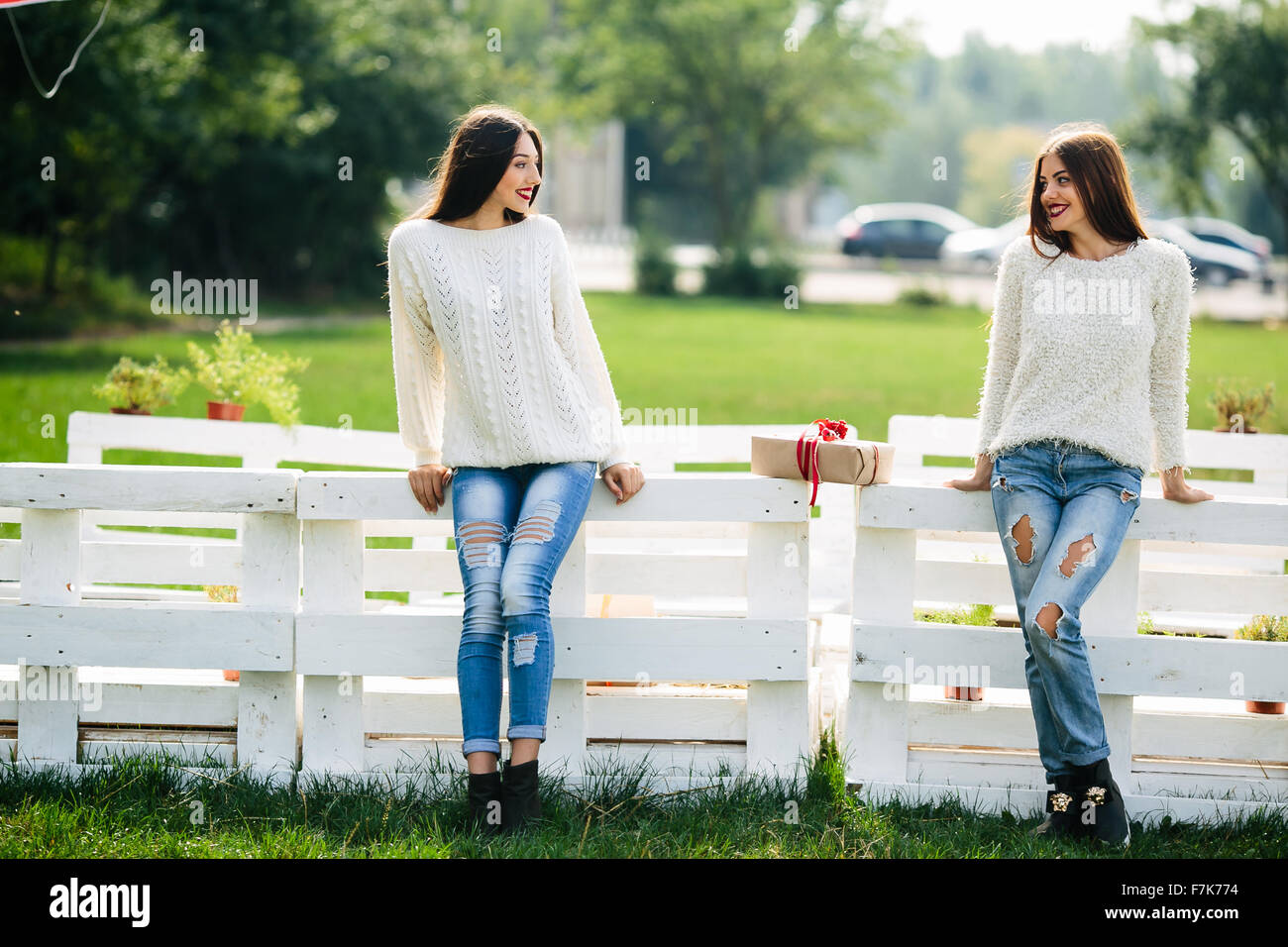 Two girls lean bench Stock Photo - Alamy