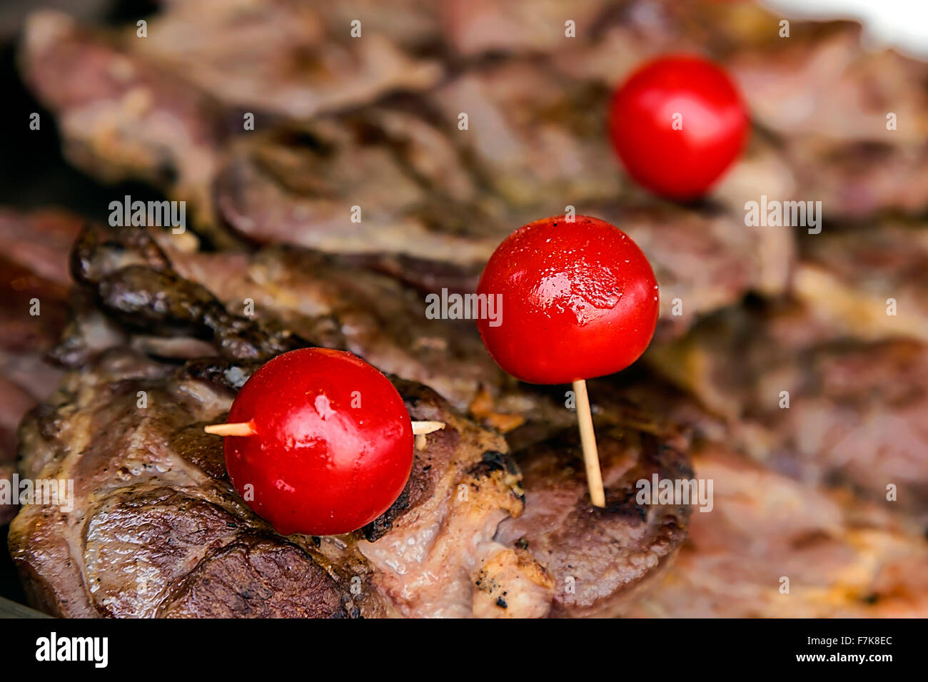Pieces of steak decorated with tomatoes fixed on toothpicks Stock Photo ...