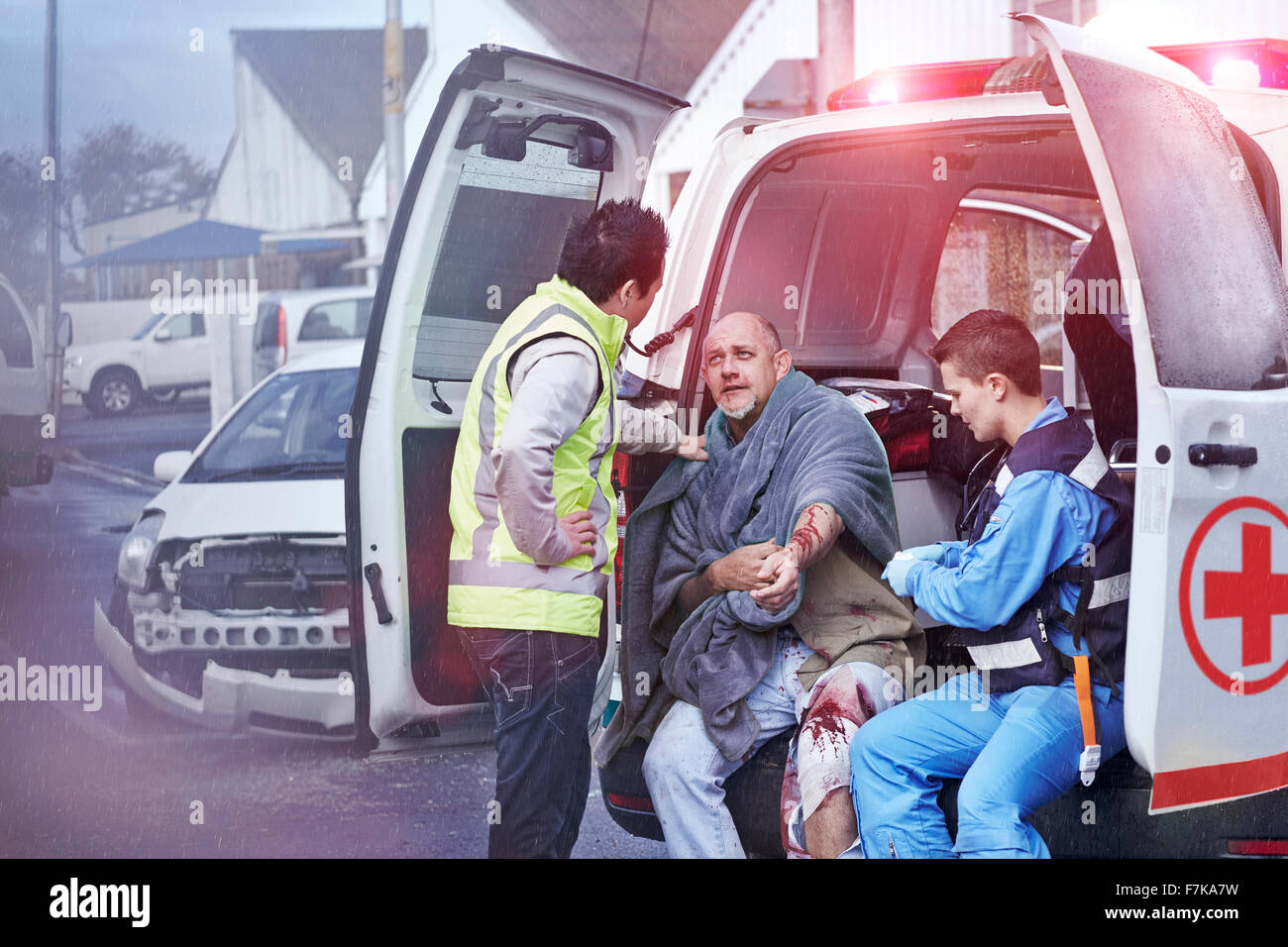 Rescue workers tending to car accident victim at back of ambulance ...