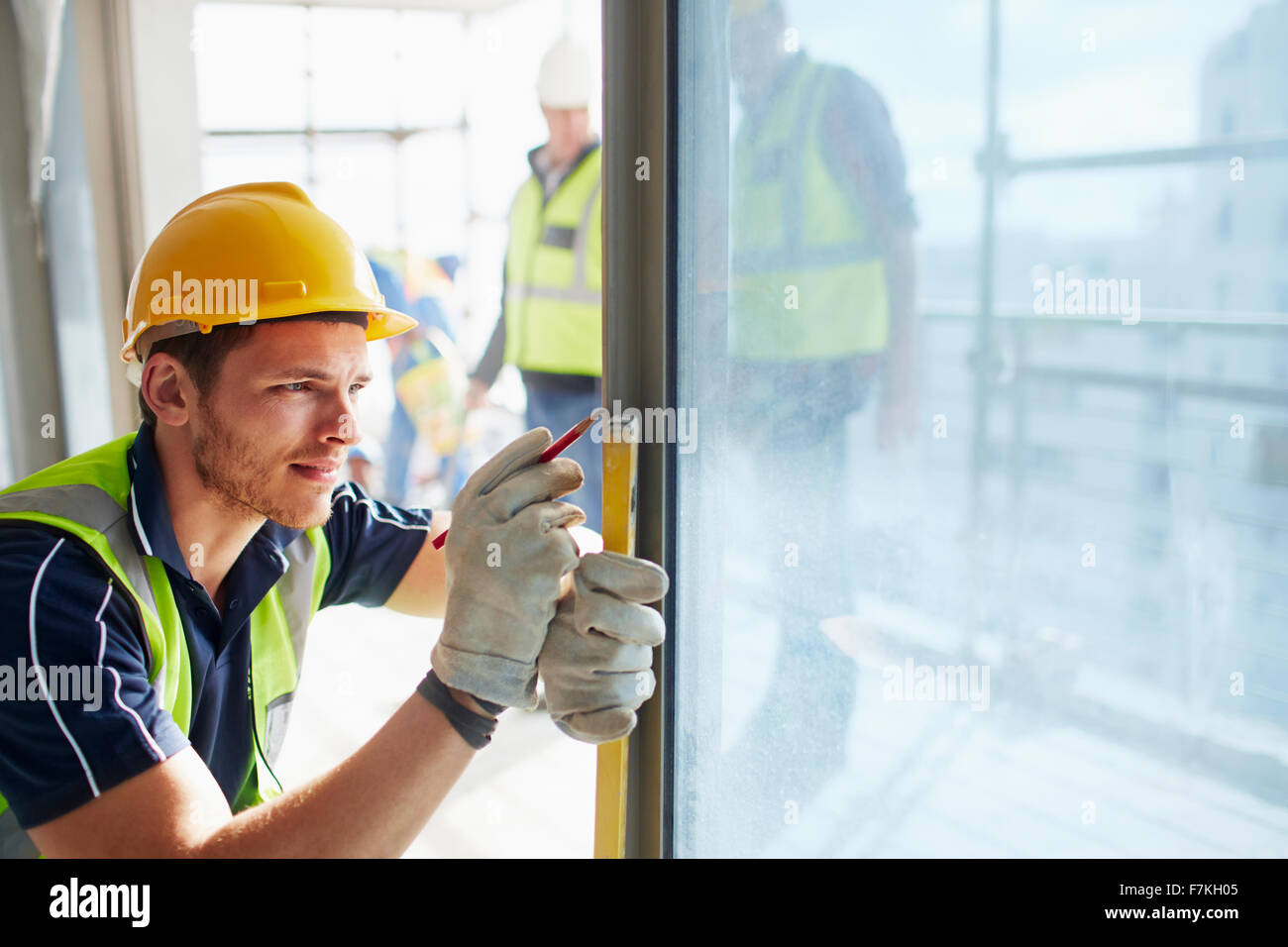Construction worker measuring window at construction site Stock Photo ...
