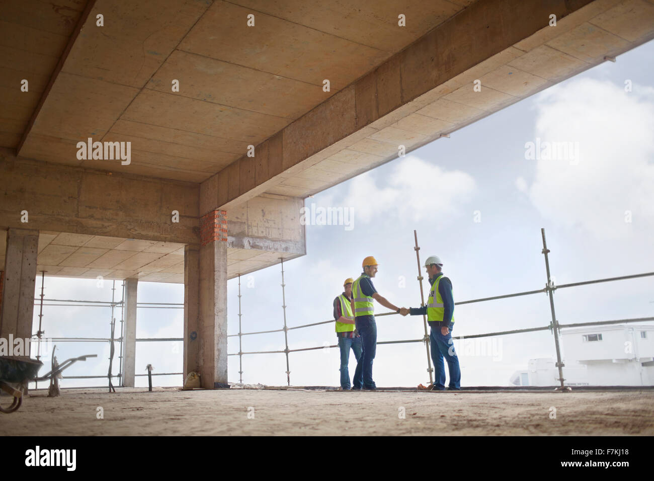 Construction workers handshaking at highrise construction site Stock ...