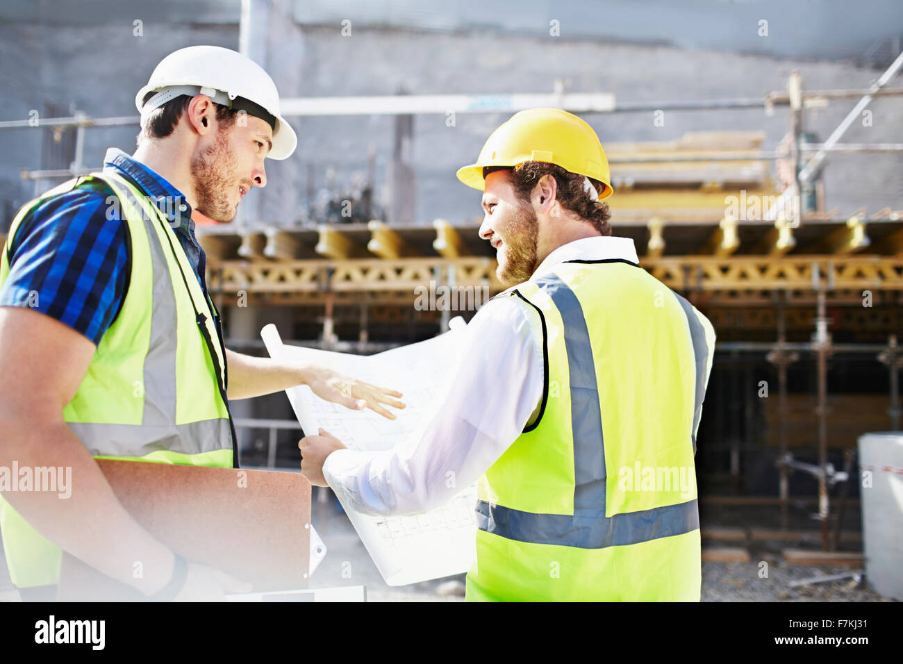 Construction worker and engineer reviewing blueprints at construction ...