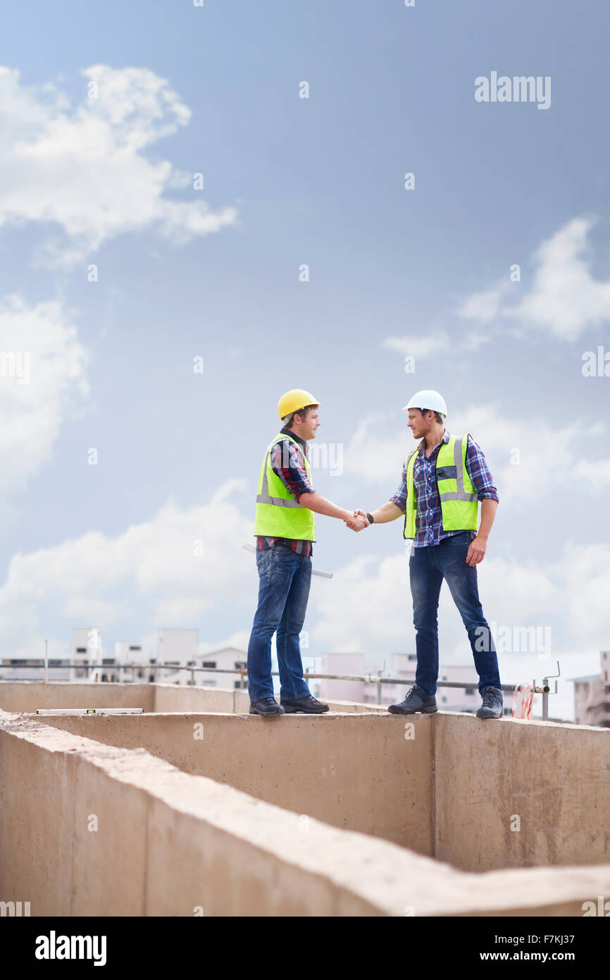 Construction workers handshaking at highrise construction site Stock ...