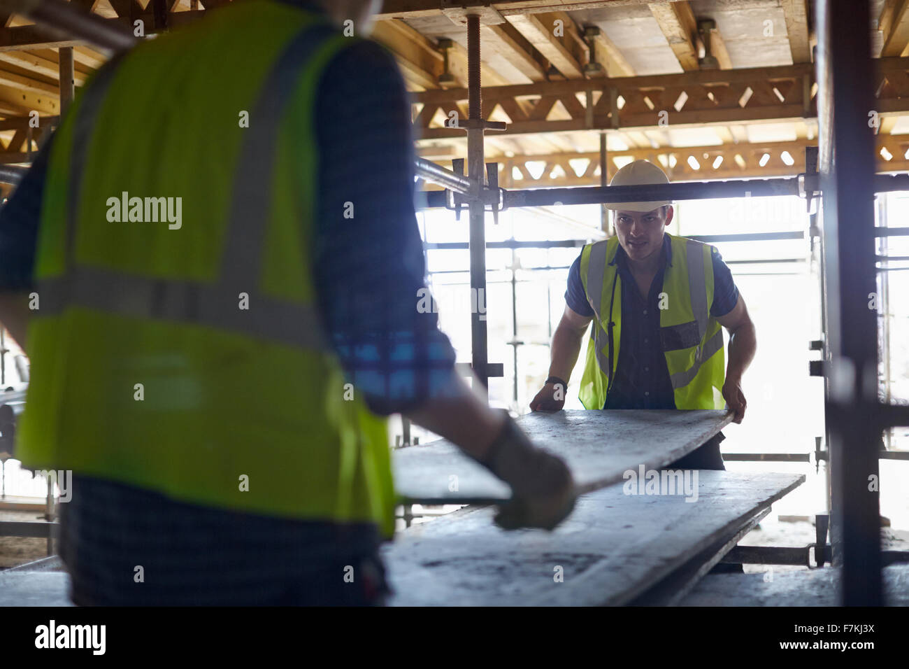 Construction workers lifting plyboard at construction site Stock Photo ...