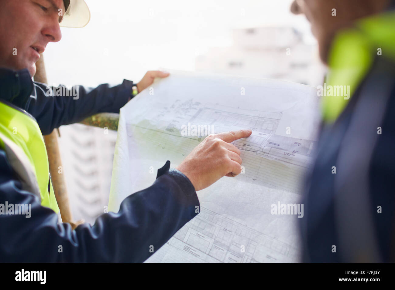 Engineers discussing blueprints at construction site Stock Photo - Alamy