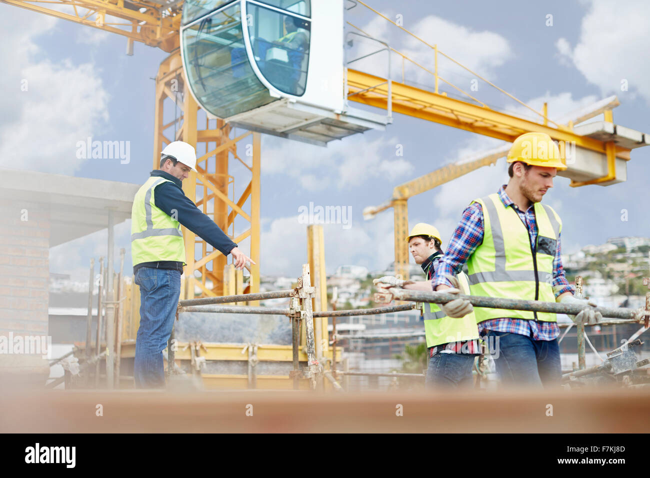 Foreman guiding construction workers below crane at construction site ...
