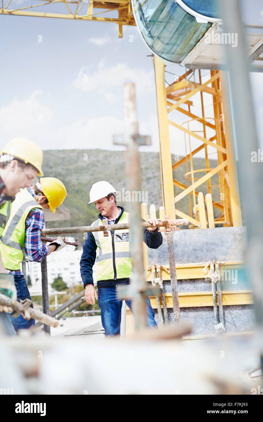 Construction workers assembling structure at highrise construction site ...