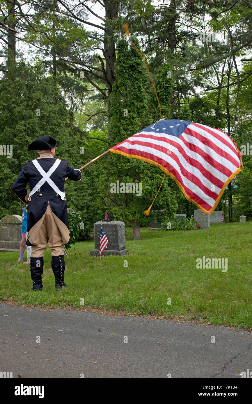 A Revolutionary Reenactor honors dead with an American Flag outside of ...