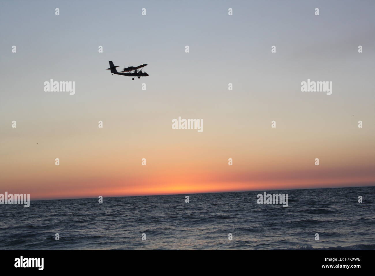 Plane over the ocean at sunset Stock Photo - Alamy