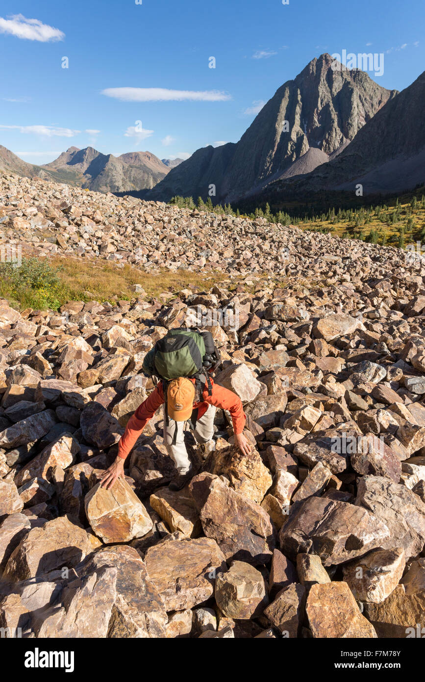 Backpacker hiking on a talus slope in Colorado's Weminuche Wilderness ...