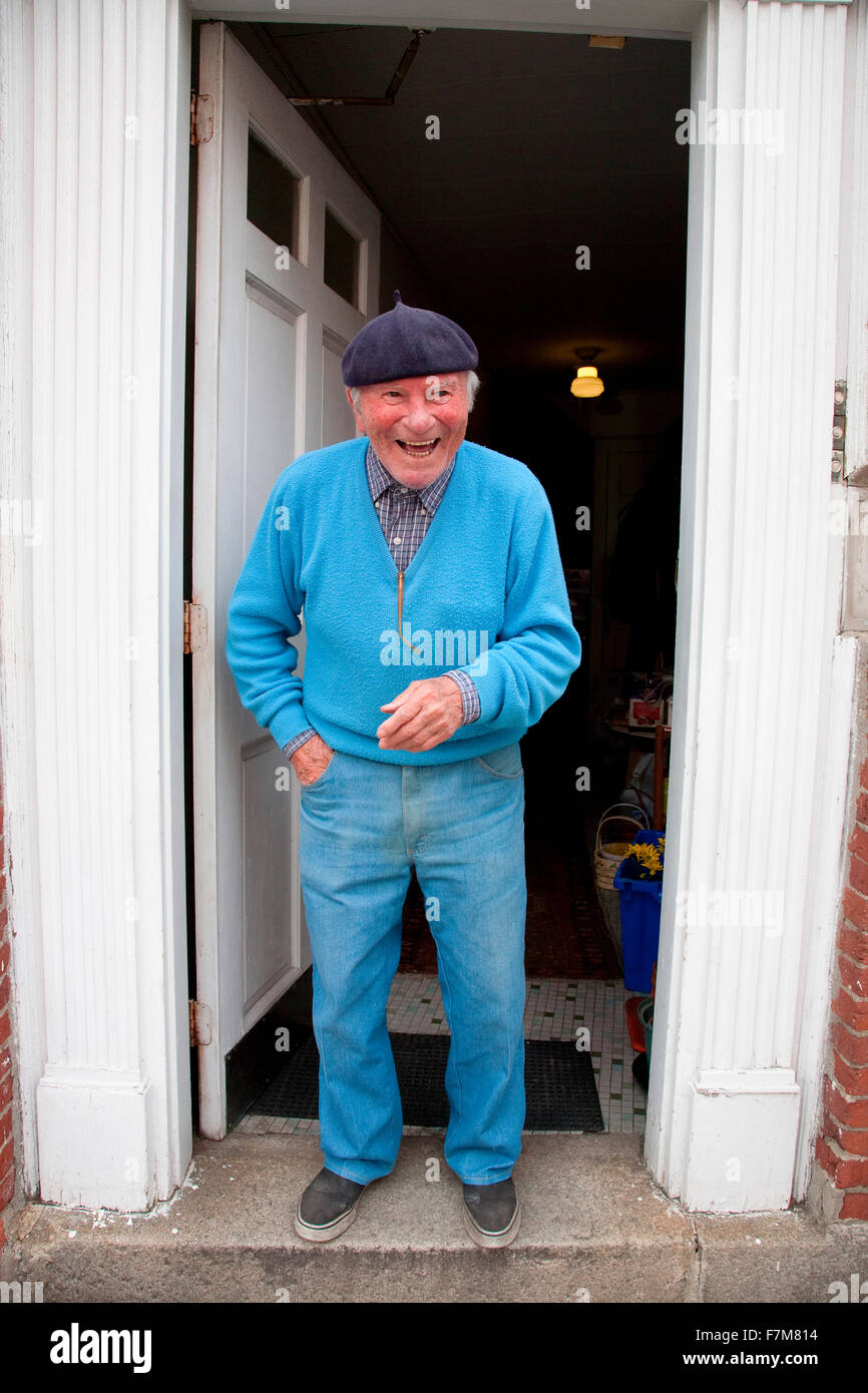 Senior Italian-American man in blue seater and matching hat gestures ...