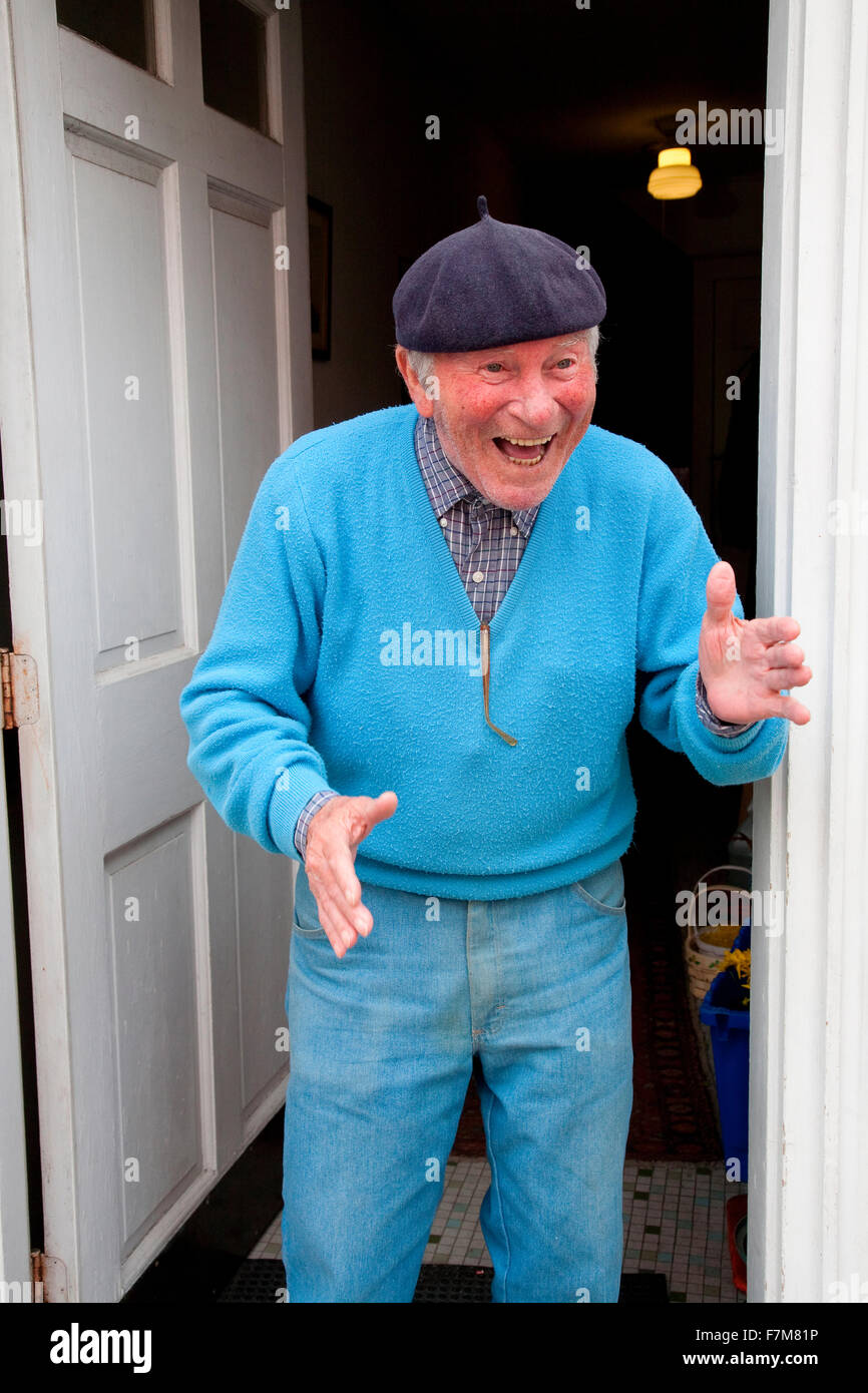 Senior Italian-American man in blue seater and matching hat gestures ...