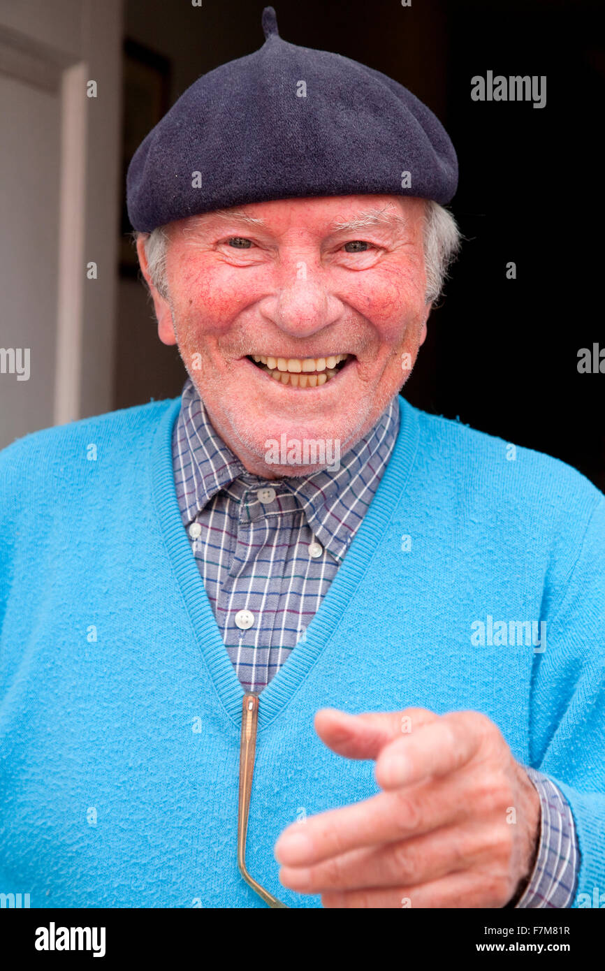 Senior Italian-American man in blue seater and matching hat gestures ...