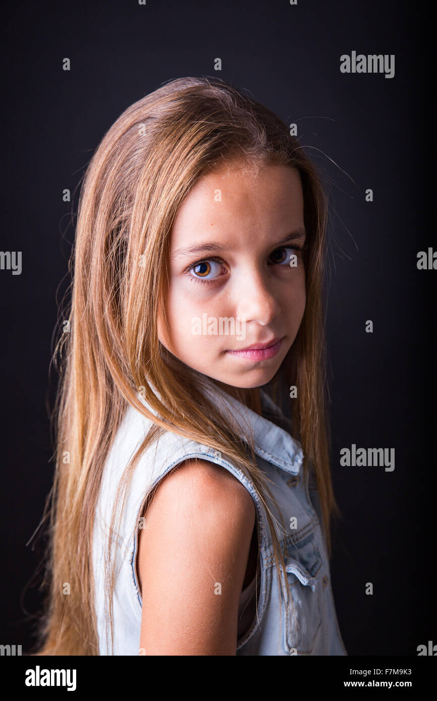 Young girl with long hair and denim jacket posing with a sober look on ...