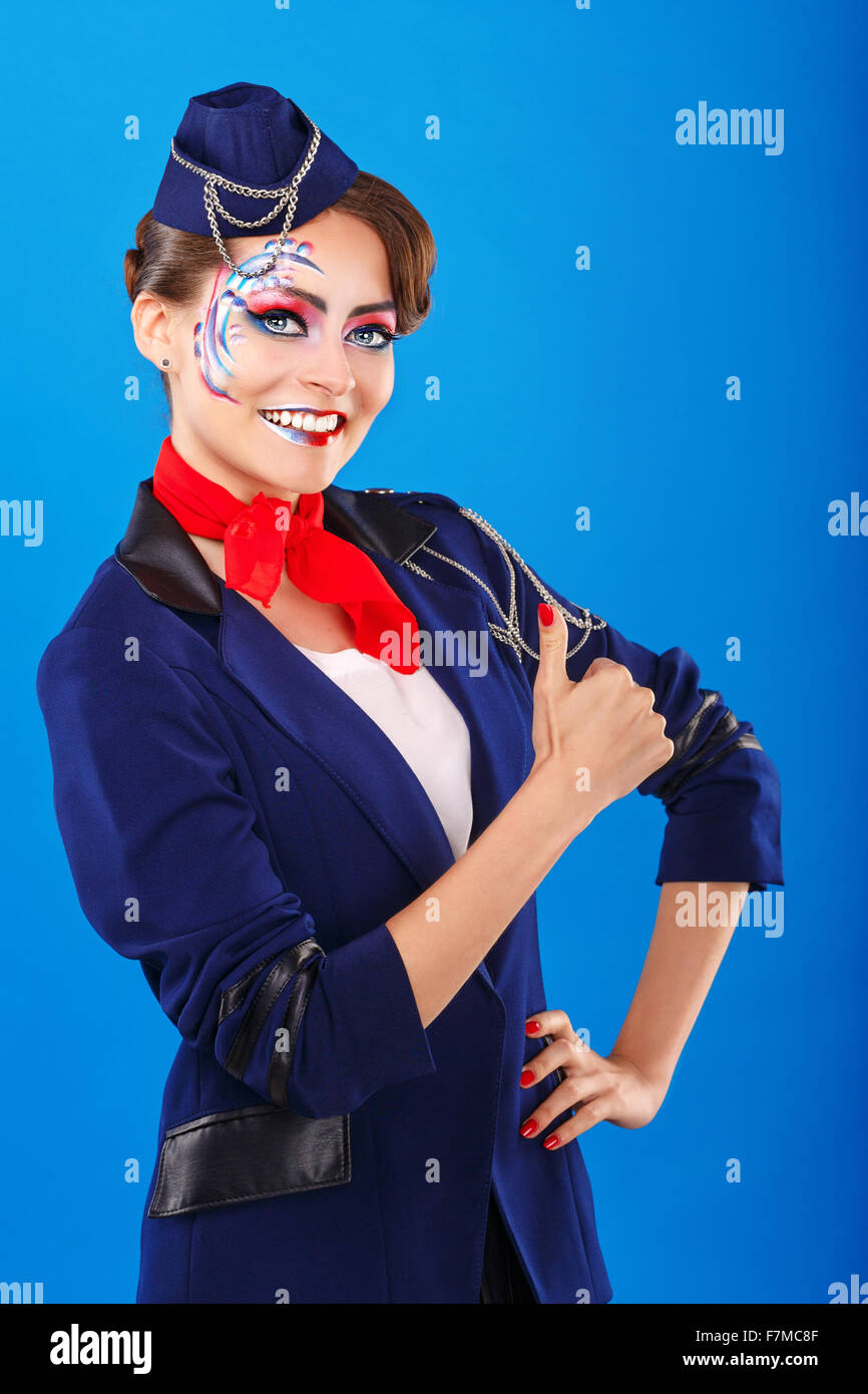 Stewardess with face art shows thumb up. Young attractive girl in a ...