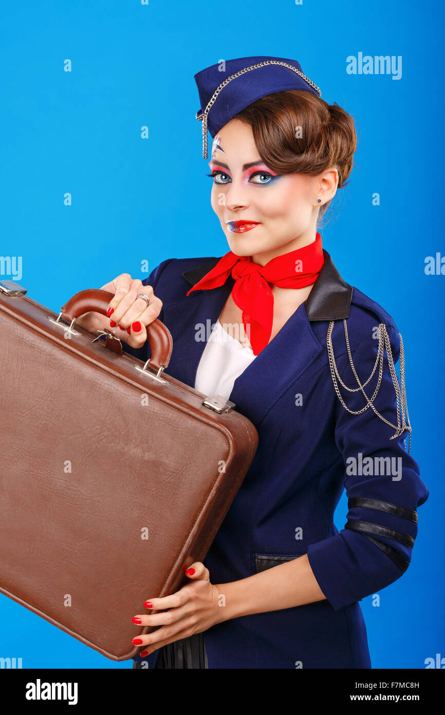 Stewardess with face art holds suitcase. Young attractive girl in a ...