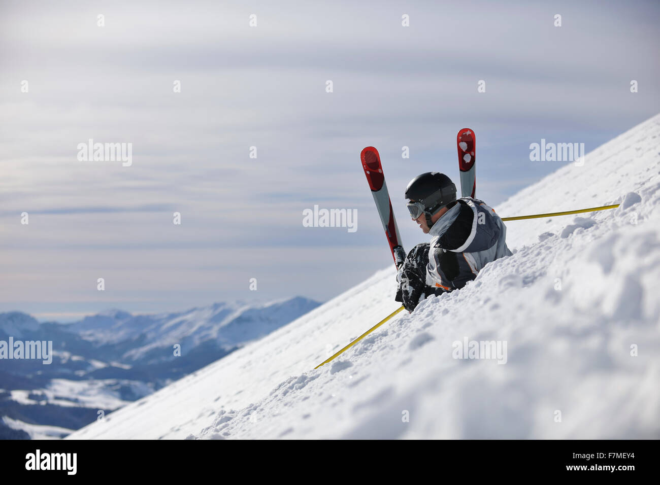 young skier relaxing in snow and looking mountain range at beautiful ...