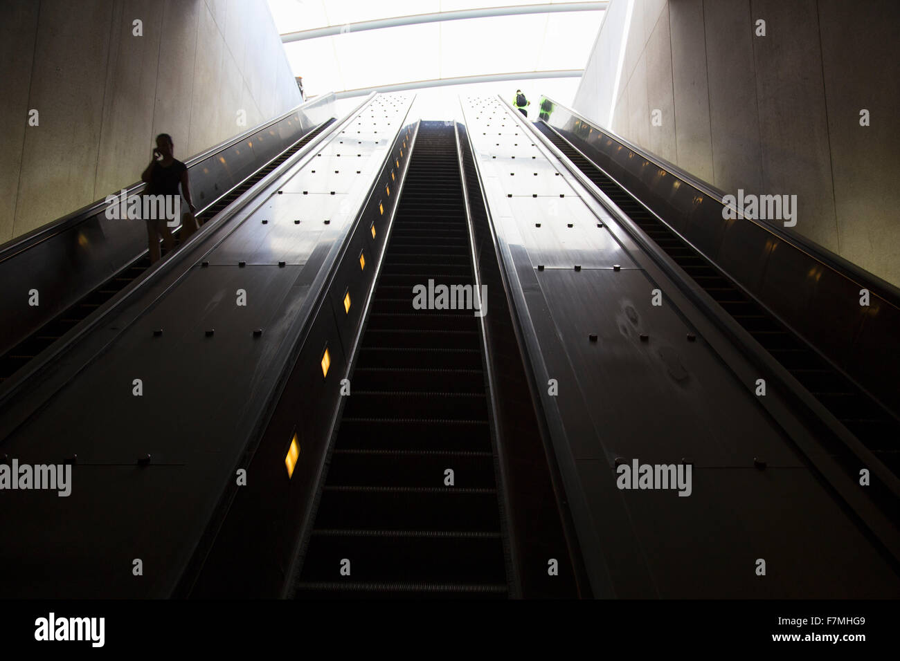 An escalator with passengers moves through oval tube of light to the ...
