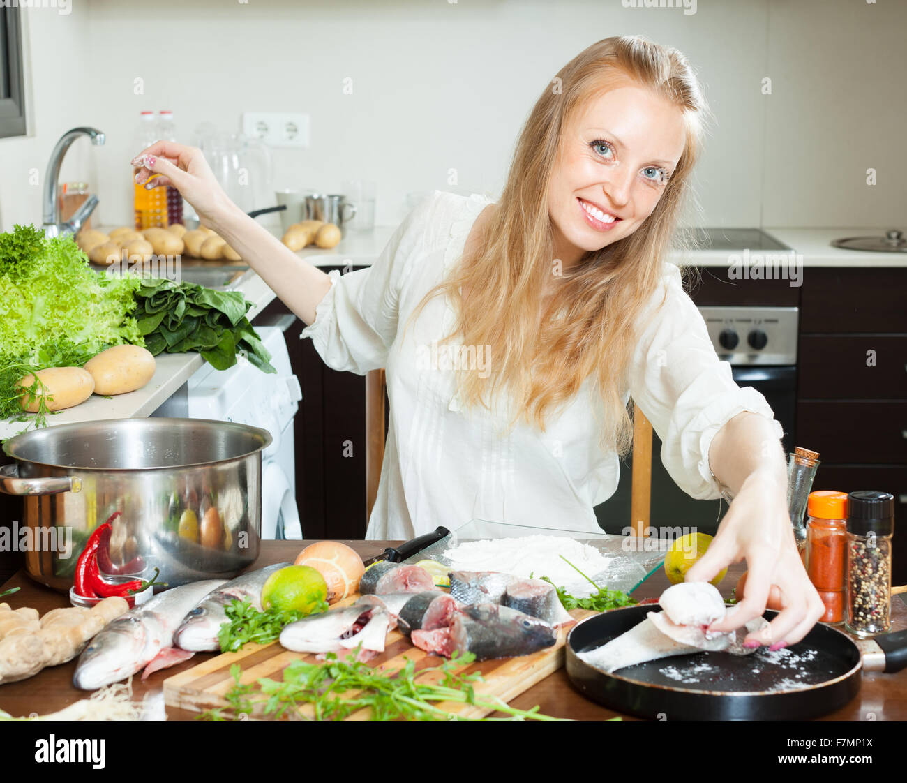 woman putting sliced fish in flour into frying pan at kitchen Stock ...