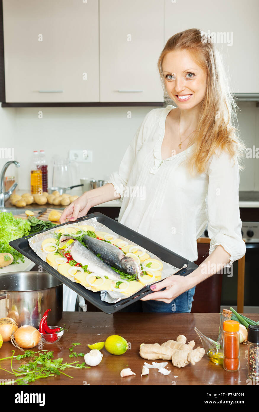 Smiling woman cooking fish with potato in sheet pan Stock Photo - Alamy