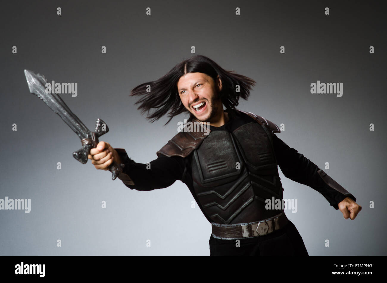 Angry knight with sword against dark background Stock Photo - Alamy