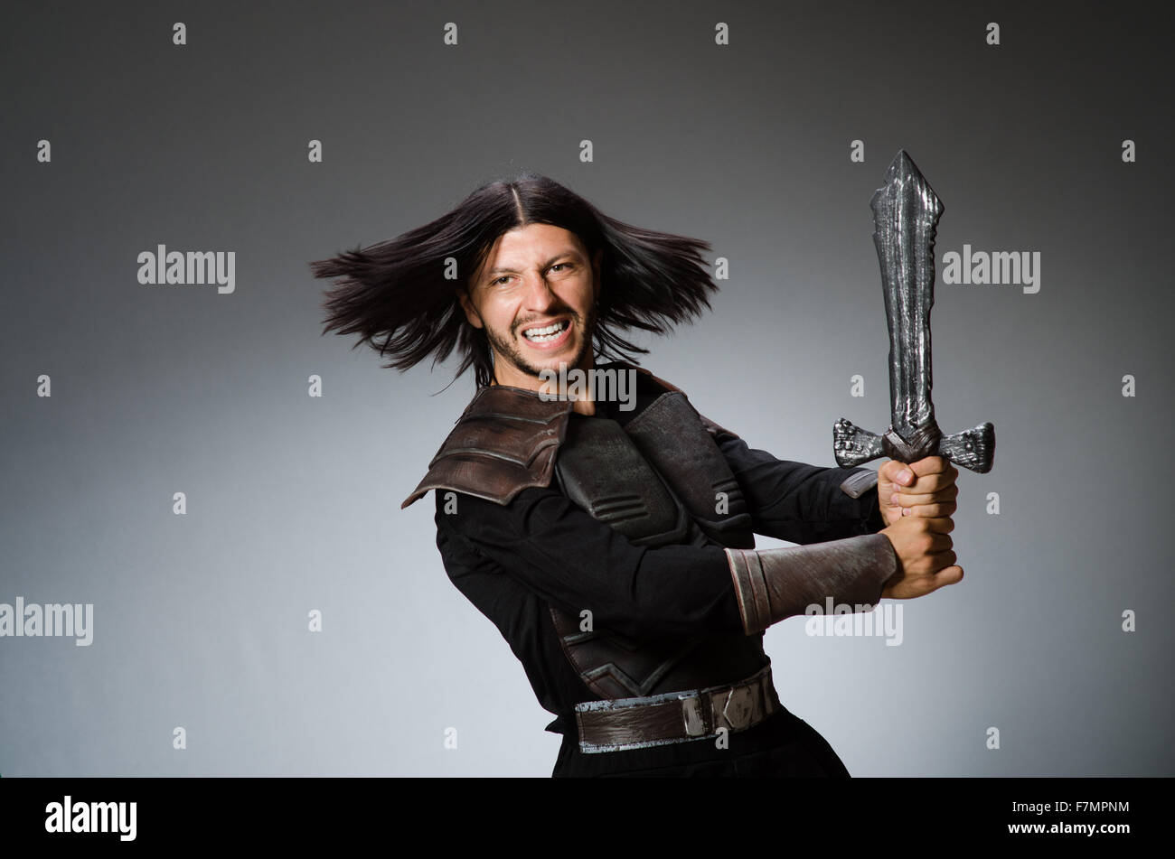 Angry knight with sword against dark background Stock Photo - Alamy