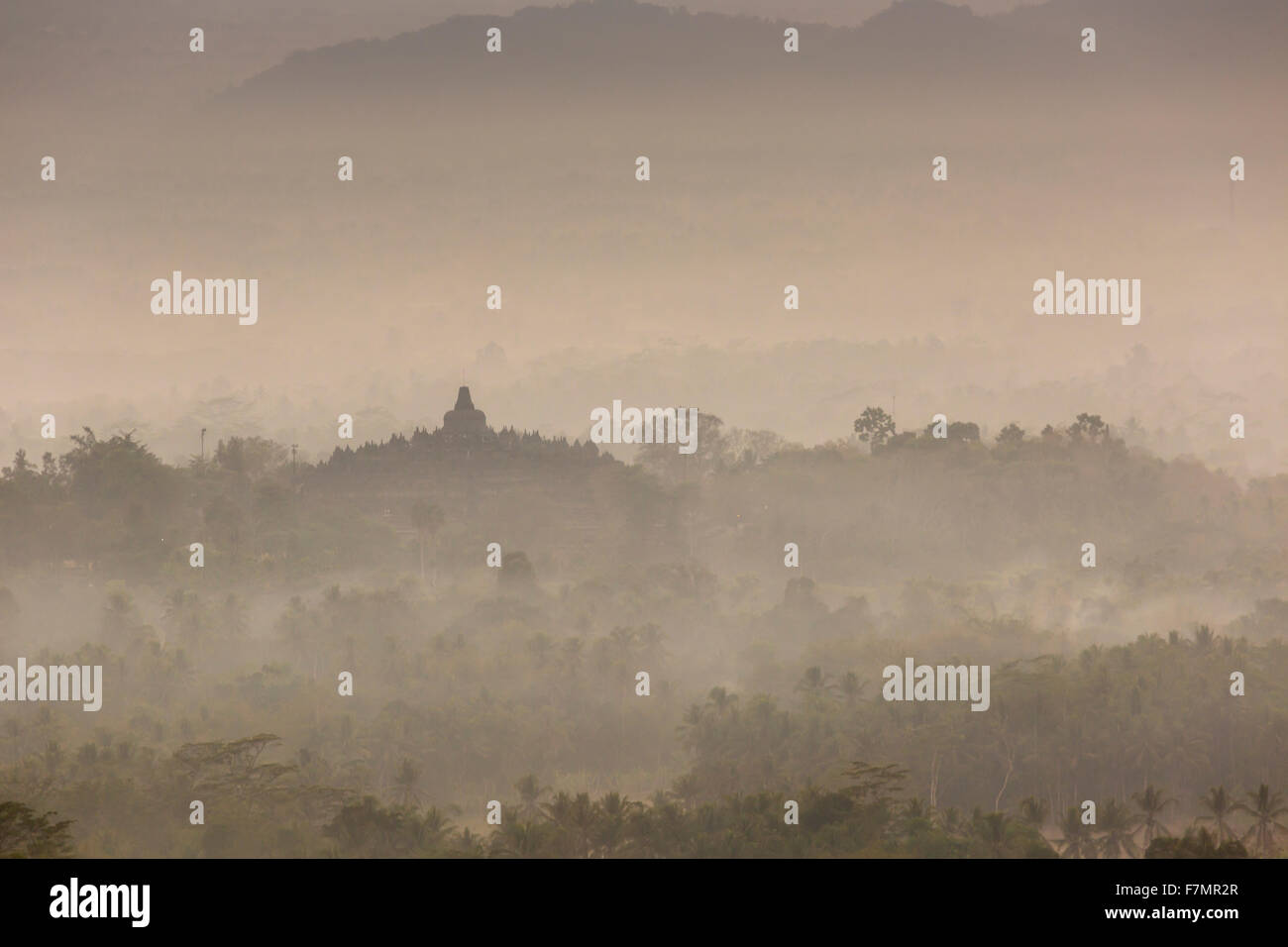 Colorful sunrise over Merapi volcano and Borobudur temple in misty ...