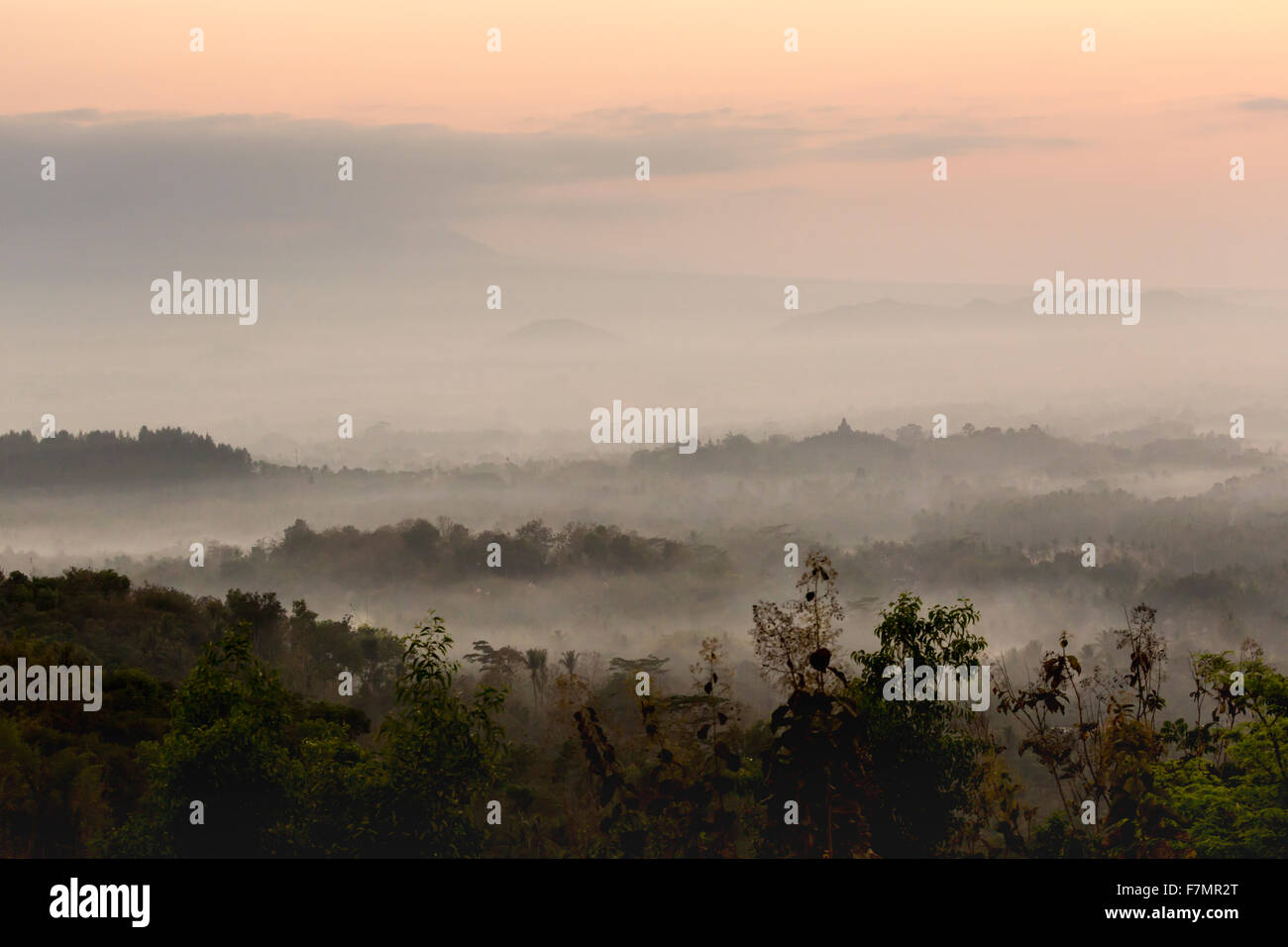 Colorful sunrise over Merapi volcano and Borobudur temple in misty ...