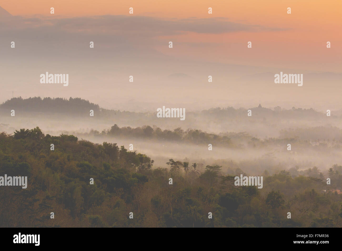 Colorful sunrise over Merapi volcano and Borobudur temple in misty ...