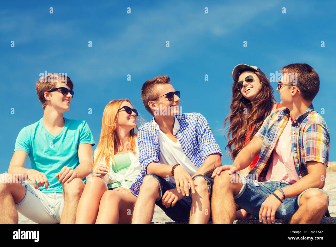 group of smiling friends sitting on city street Stock Photo - Alamy