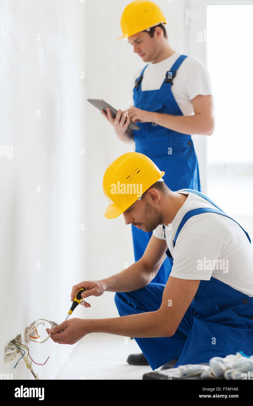builders with tablet pc and fixing wiring indoors Stock Photo - Alamy