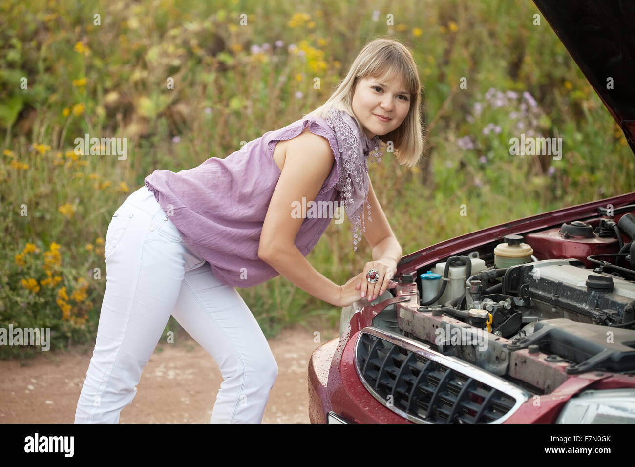 Blonde woman trying to fix the car Stock Photo - Alamy