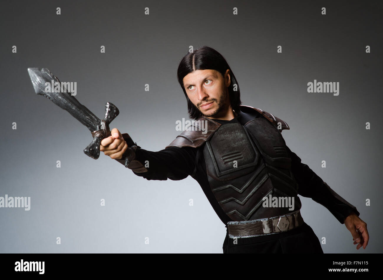 Angry knight with sword against dark background Stock Photo - Alamy
