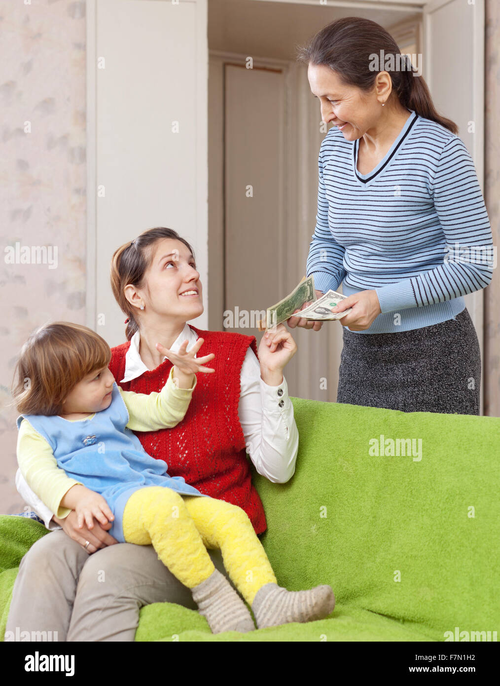 Mother pays nanny for her child at home Stock Photo - Alamy