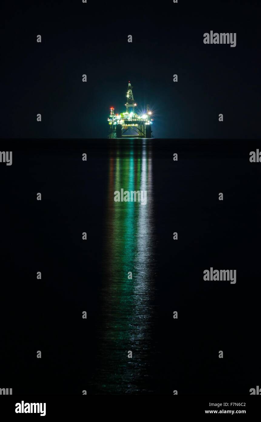A night view of the oil drilling platform lit up on the coast of ...
