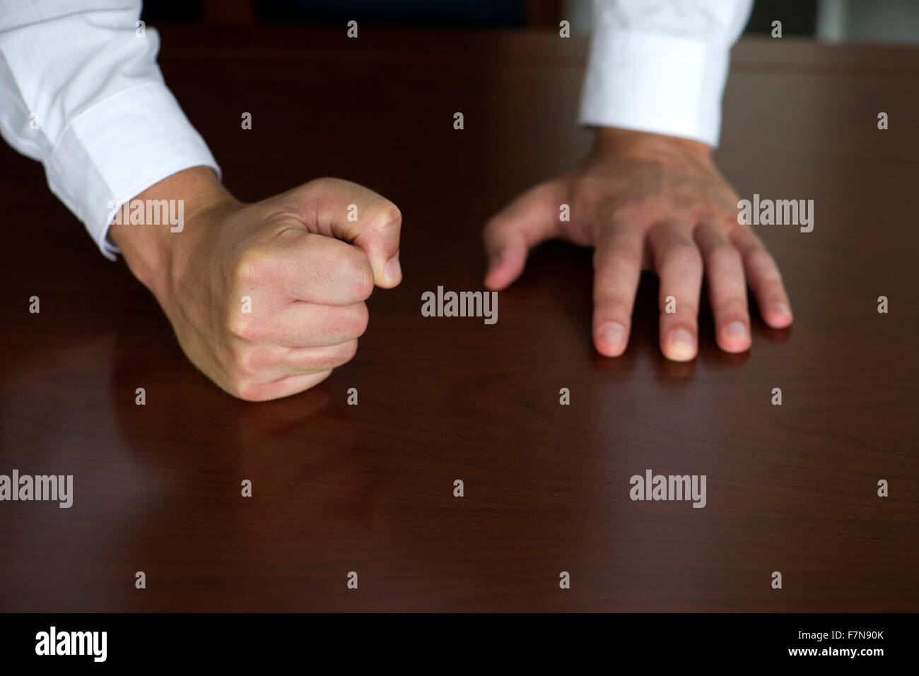 Businessman pounding fist on table, cropped Stock Photo - Alamy