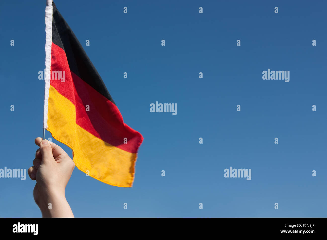 Hand is holding the germany flag against blue sky Stock Photo - Alamy