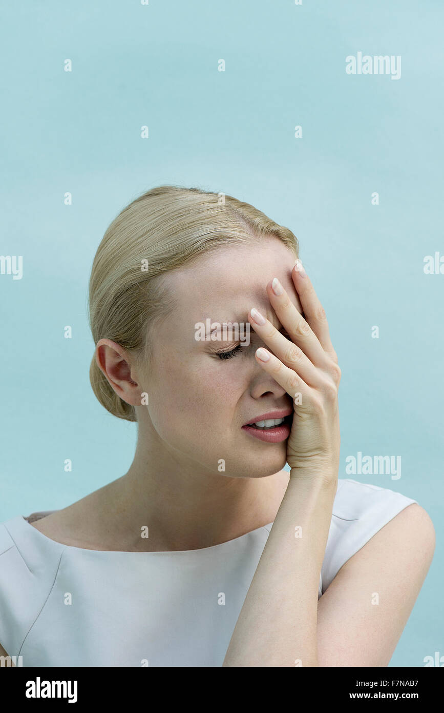 Woman covering face with hand and grimacing Stock Photo - Alamy