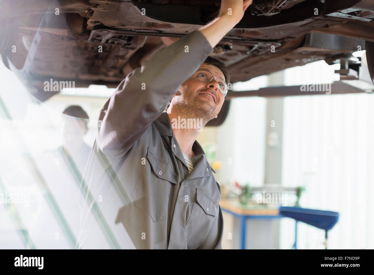 Mechanic working under car in auto repair shop Stock Photo - Alamy