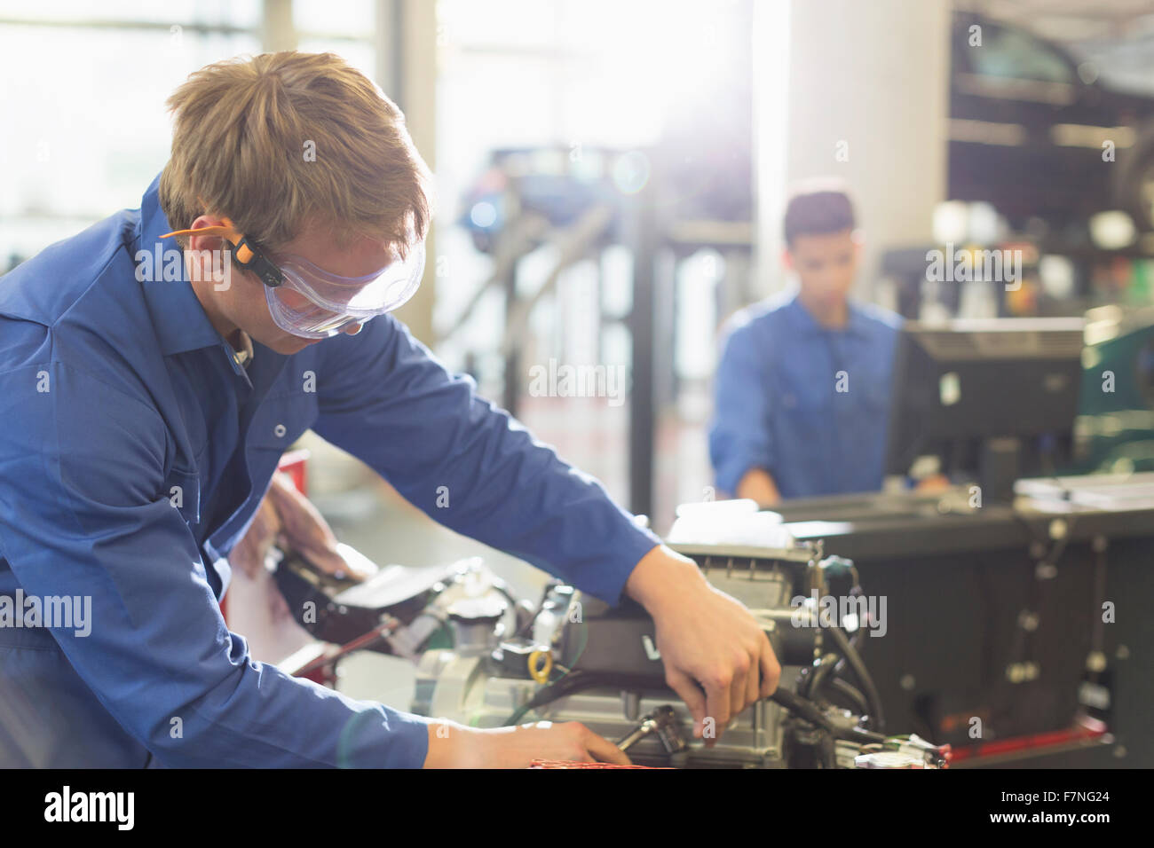 Mechanic working on engine in auto repair shop Stock Photo - Alamy