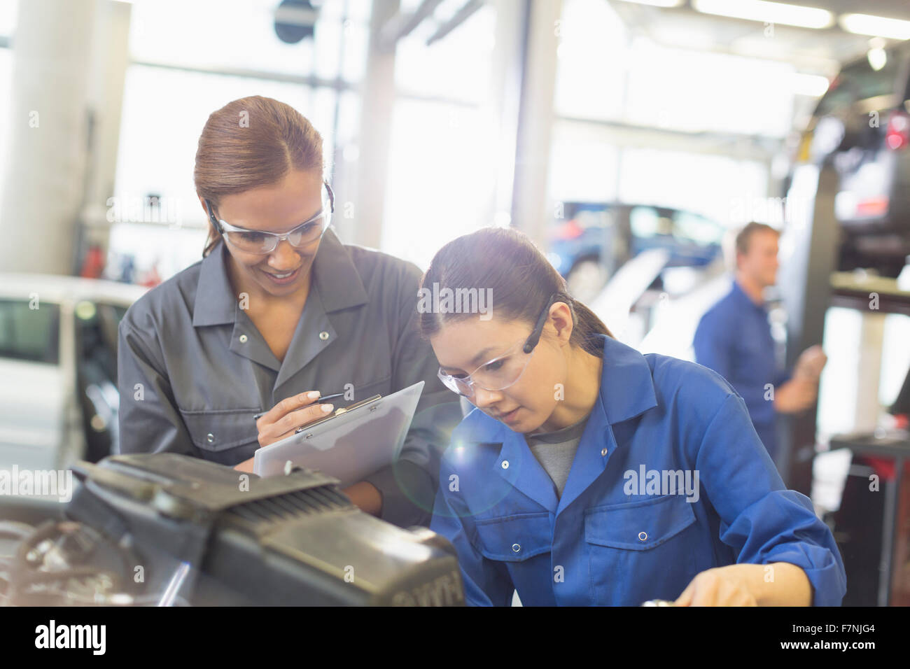 Female mechanics working on engine in auto repair shop Stock Photo - Alamy