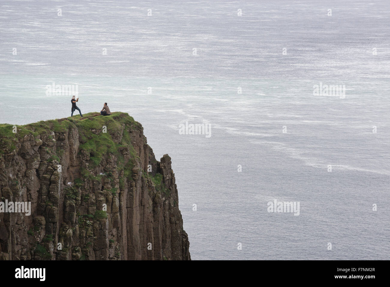 UK, Northern Ireland, County Antrim, people on rock cliff at Causeway ...