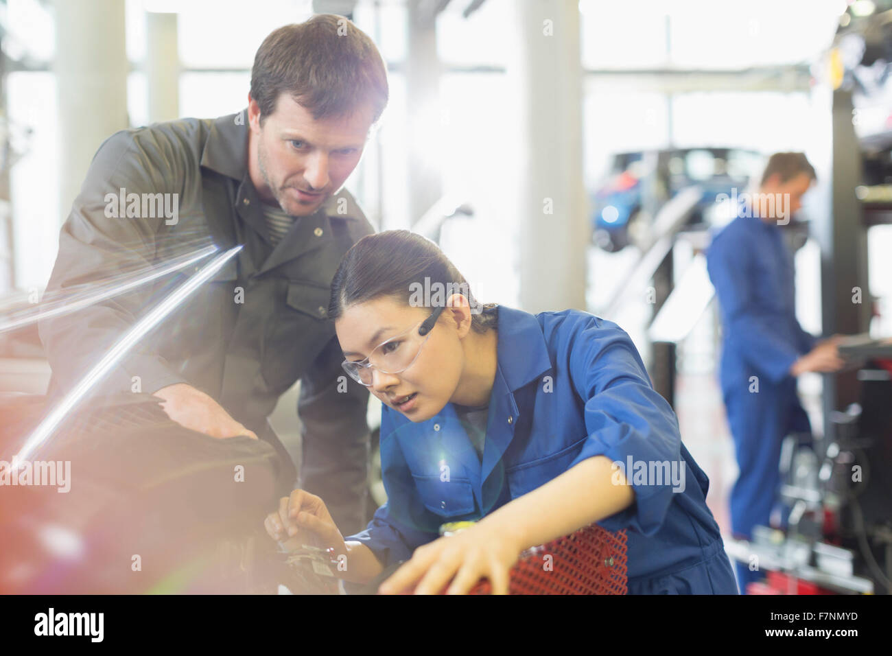 Mechanics working on engine in auto repair shop Stock Photo - Alamy