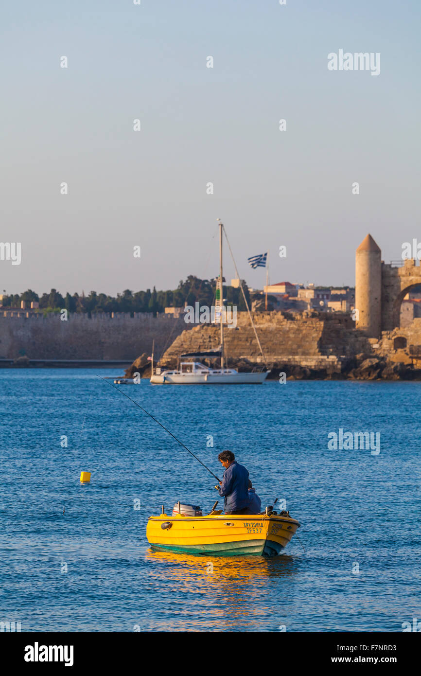 Greece, Rhodes, angler in fishing boat with harbor in background Stock ...