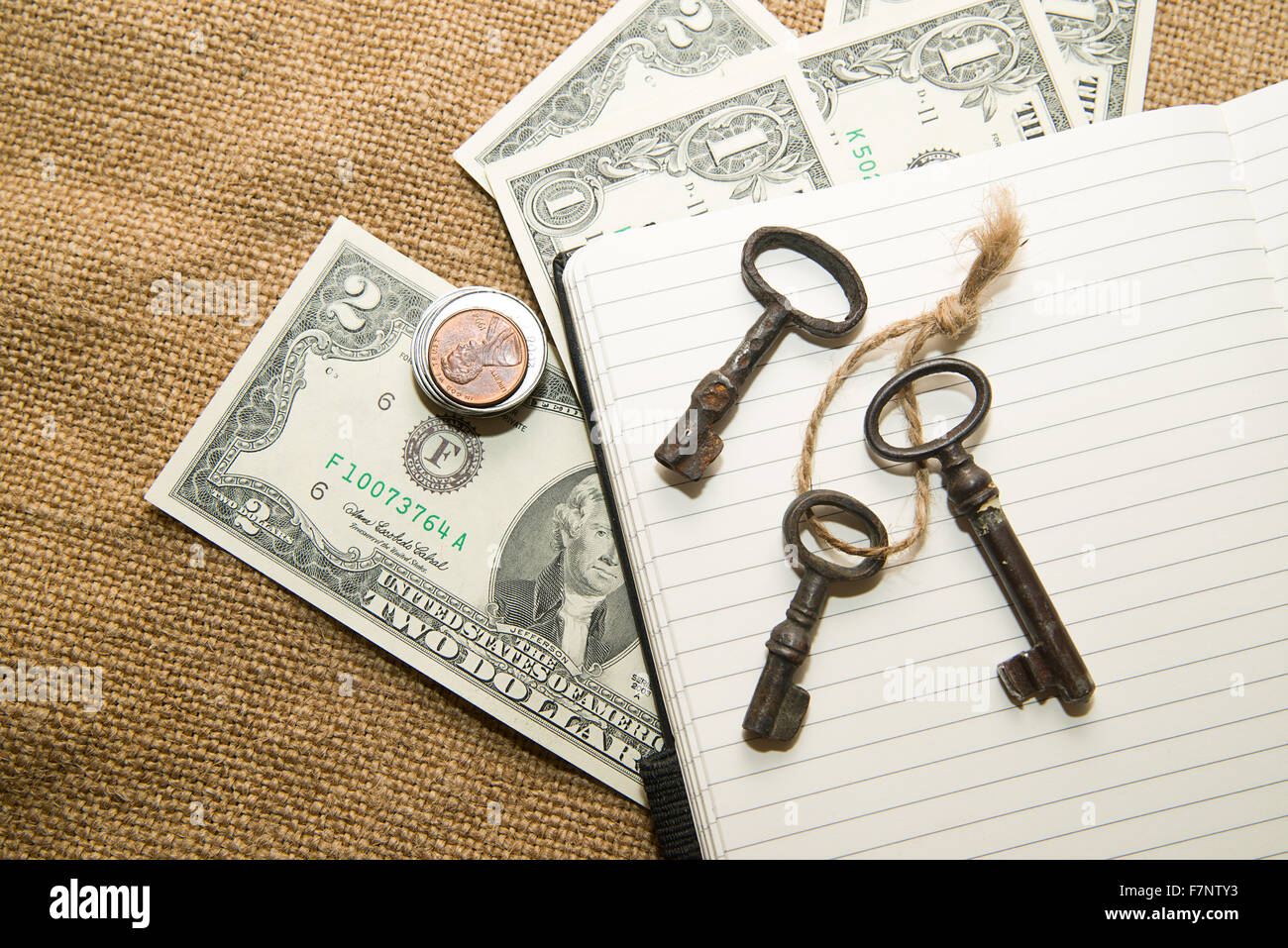 Opened notebook with a blank sheet keys and money on the old tissue ...