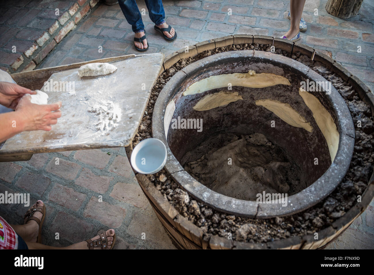 Woman shows traditional way of Shoti Bread baking in oven called tone ...