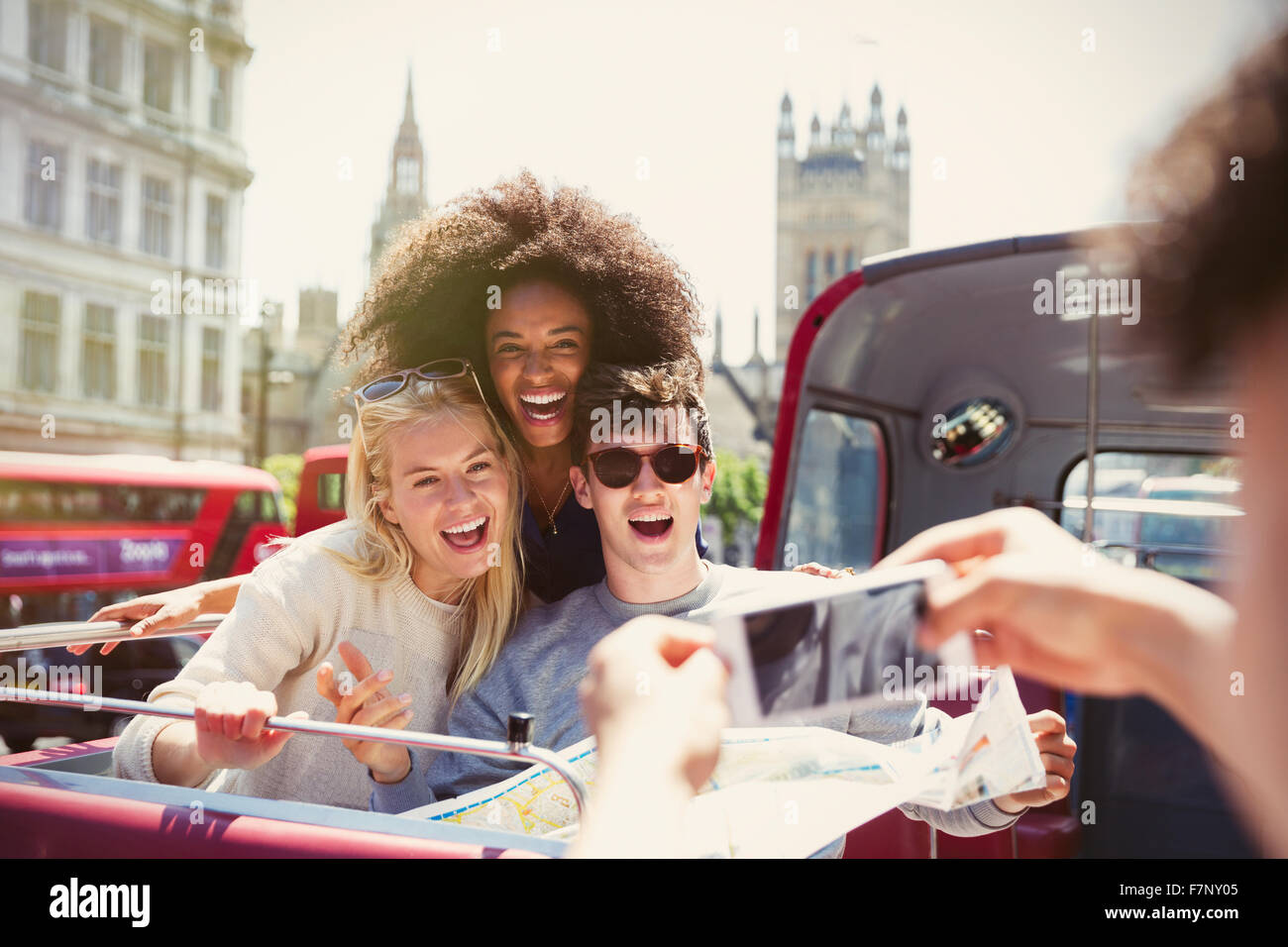 Enthusiastic friends being photographed on double-decker bus Stock ...