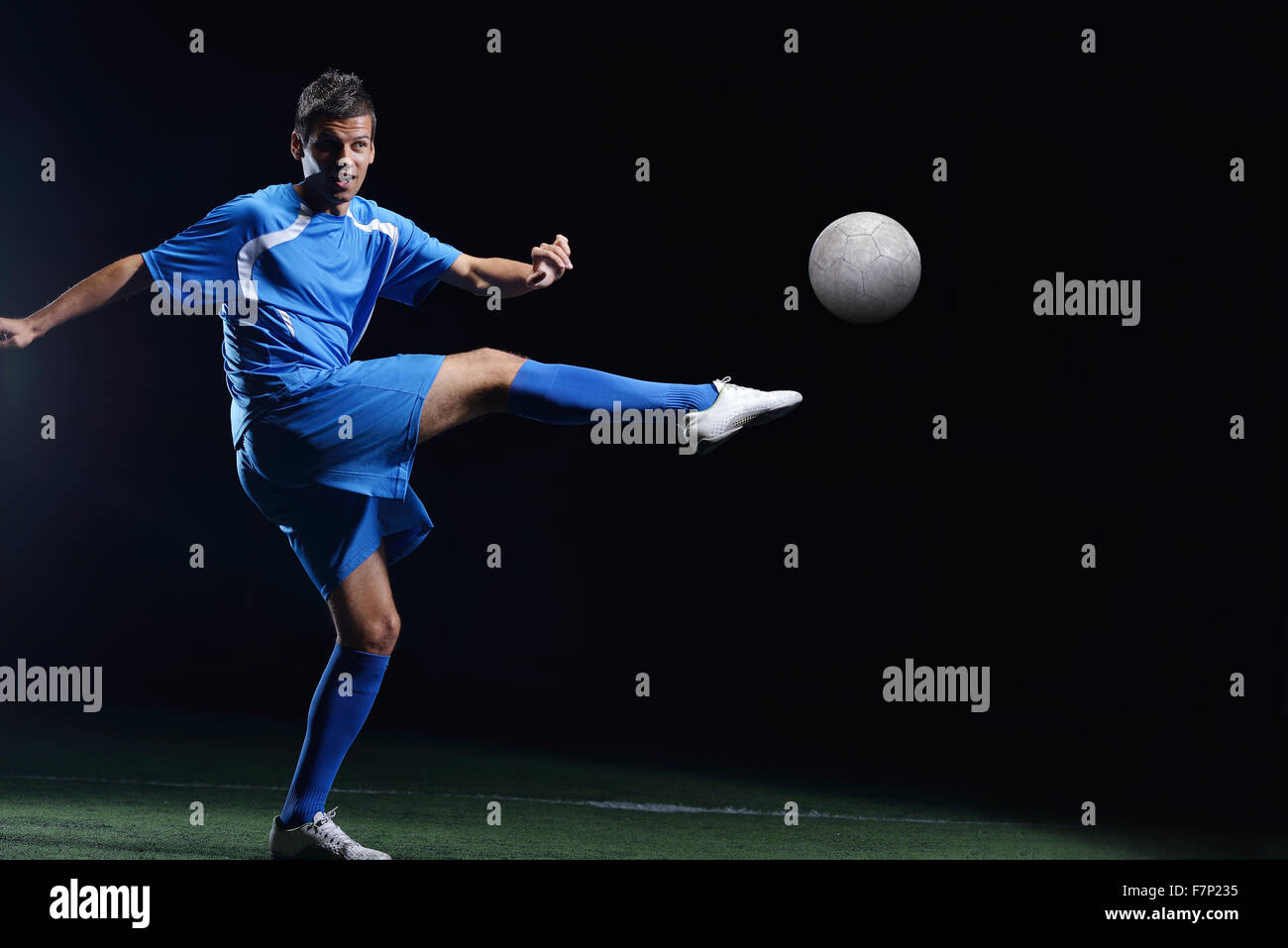 soccer player doing kick with ball on football stadium field isolated ...